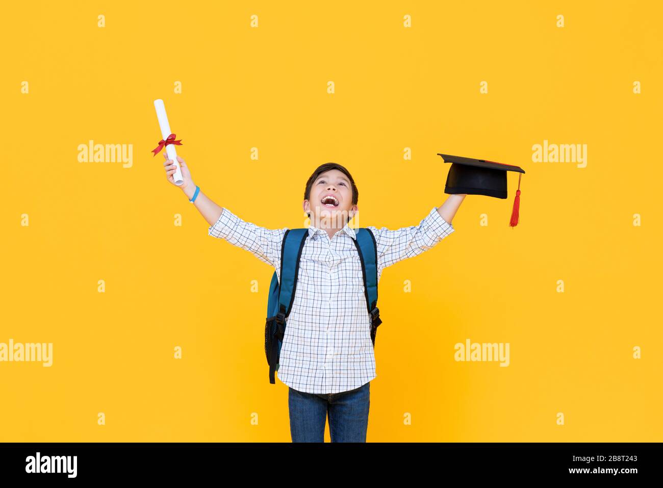 Happy graduate boy with academic cap smiling and raising hands ...