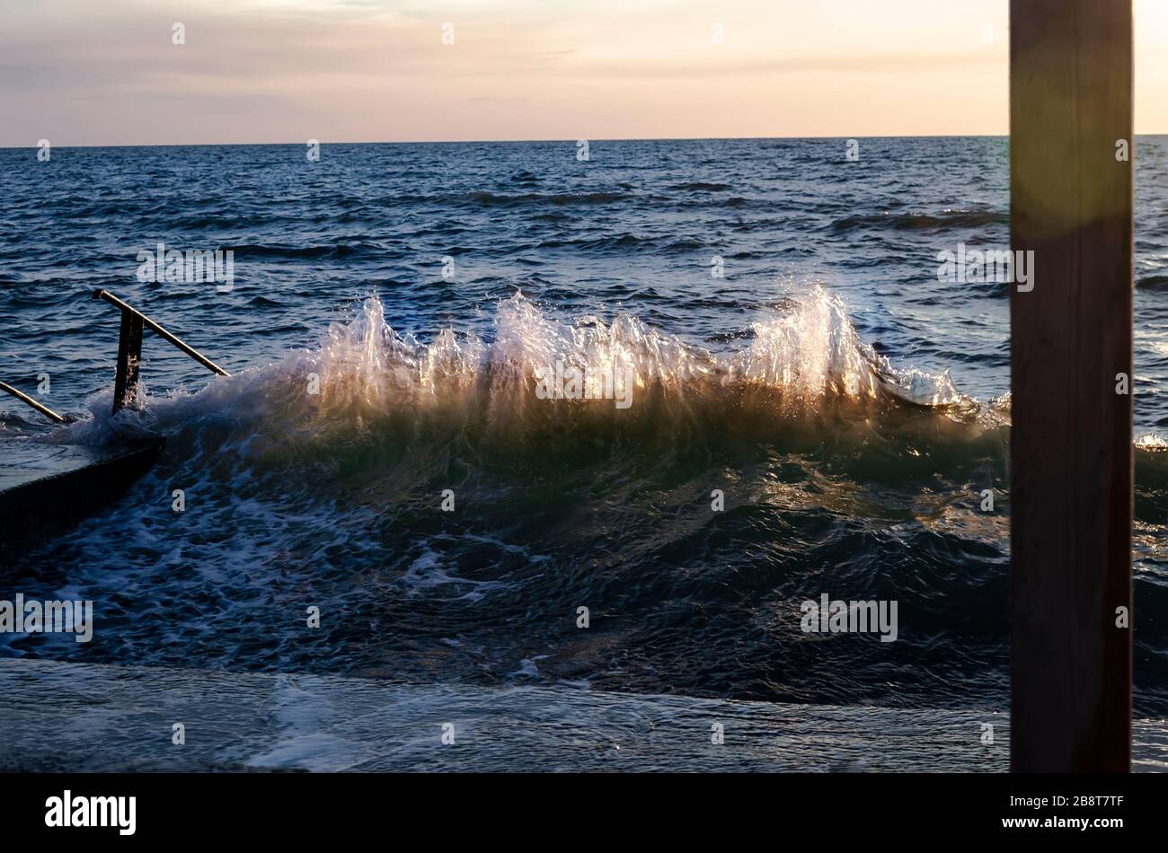 Bright sunset under the sea with waves splashes and stones Stock Photo ...