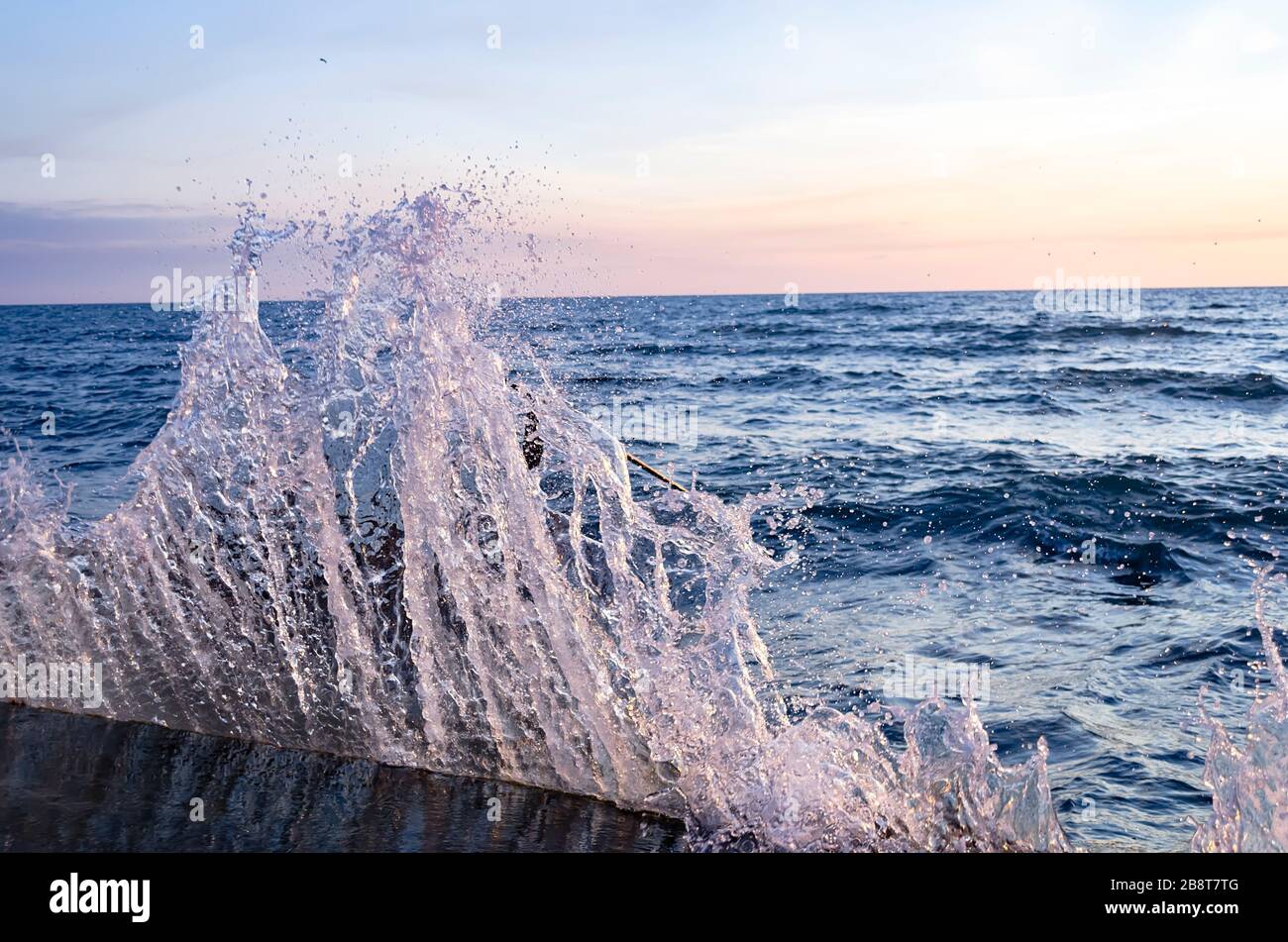 Bright sunset under the sea with waves splashes and stones Stock Photo ...
