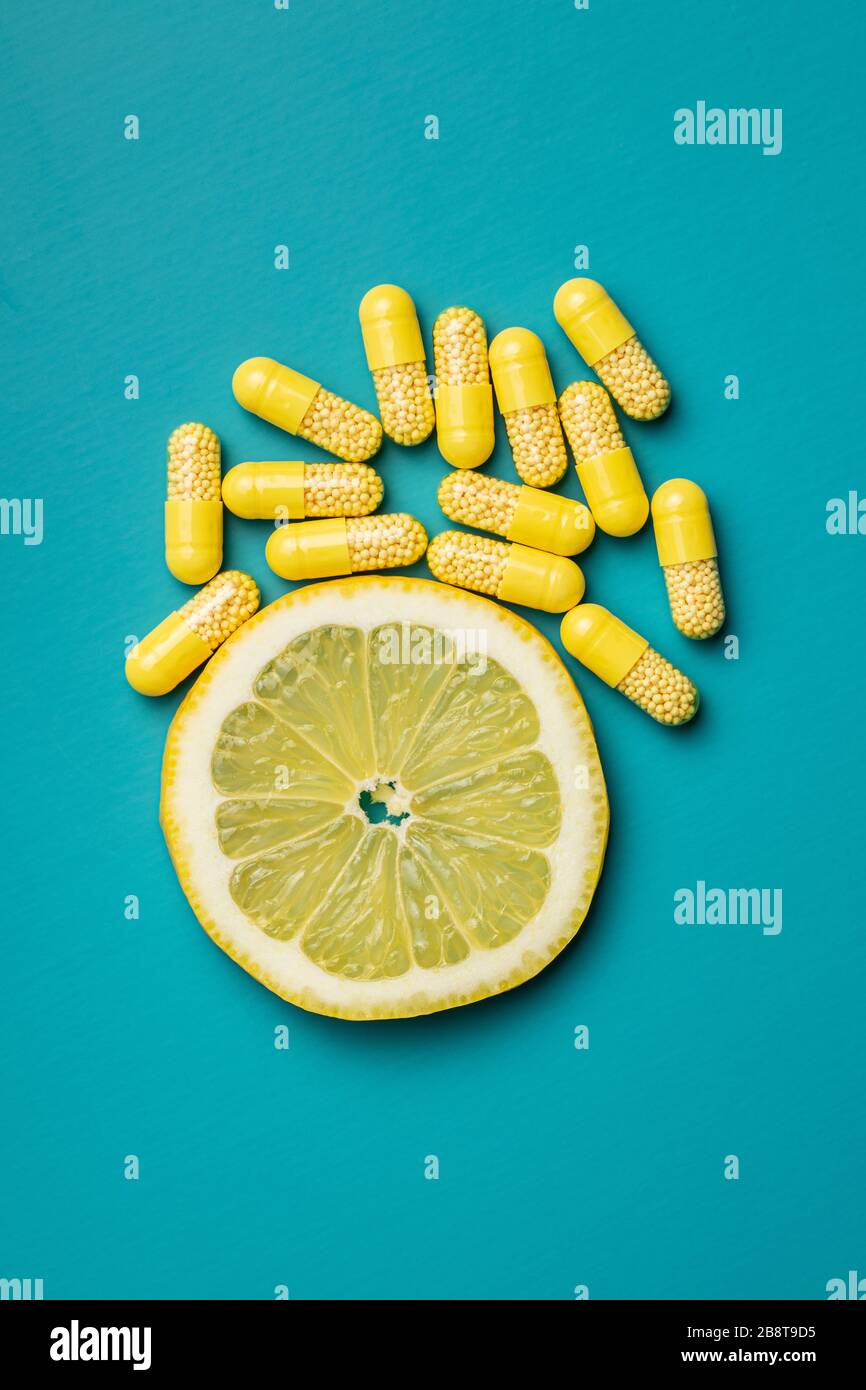 Vitamin capsules. Vitamin C pills and slice of lemon on colorful ...