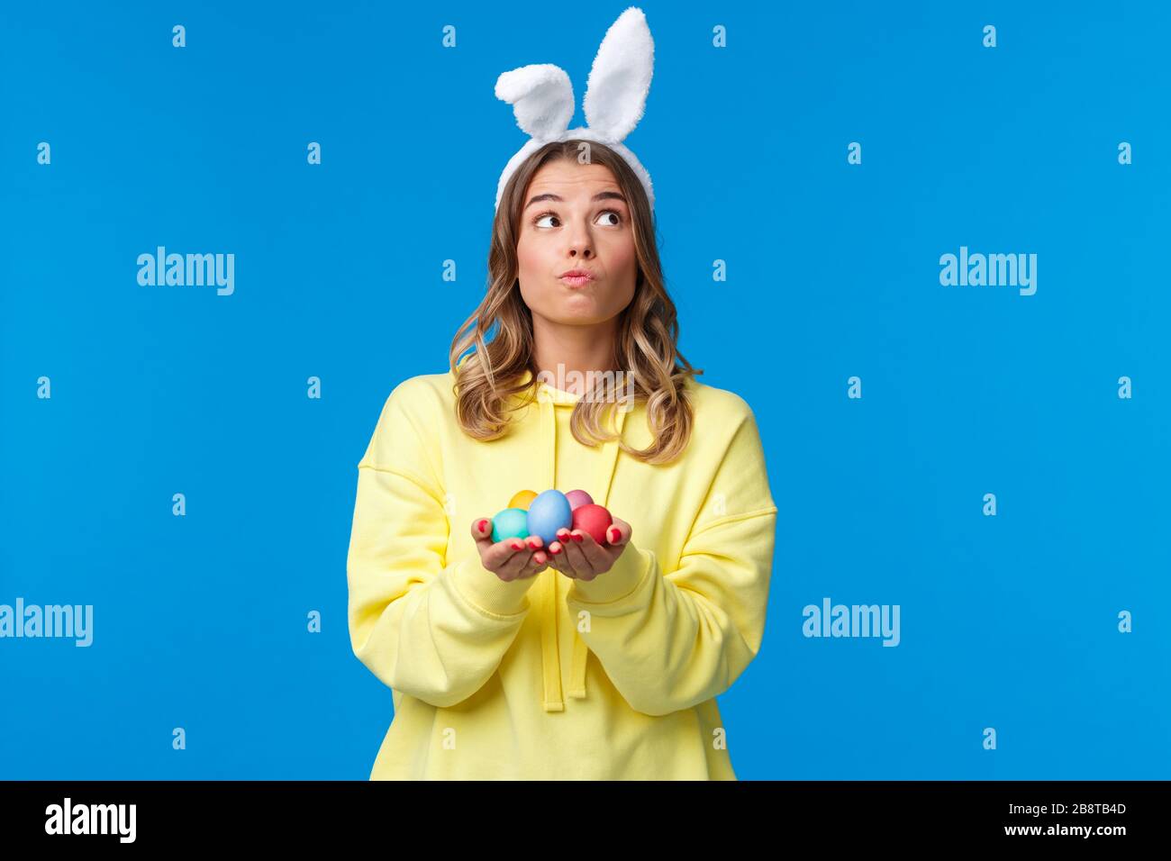 Thoughtful cute caucasian girl in rabbit ears thinking, looking up ...