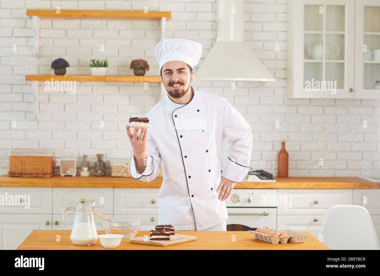 Confectioner man smiles while standing with cake in his hands at the ...