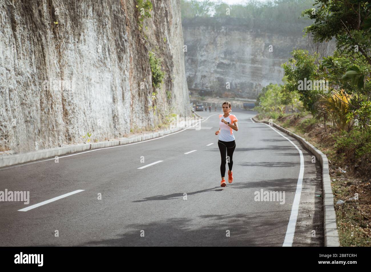 sport woman running on sideroad. fit woman jogging on empty road Stock ...