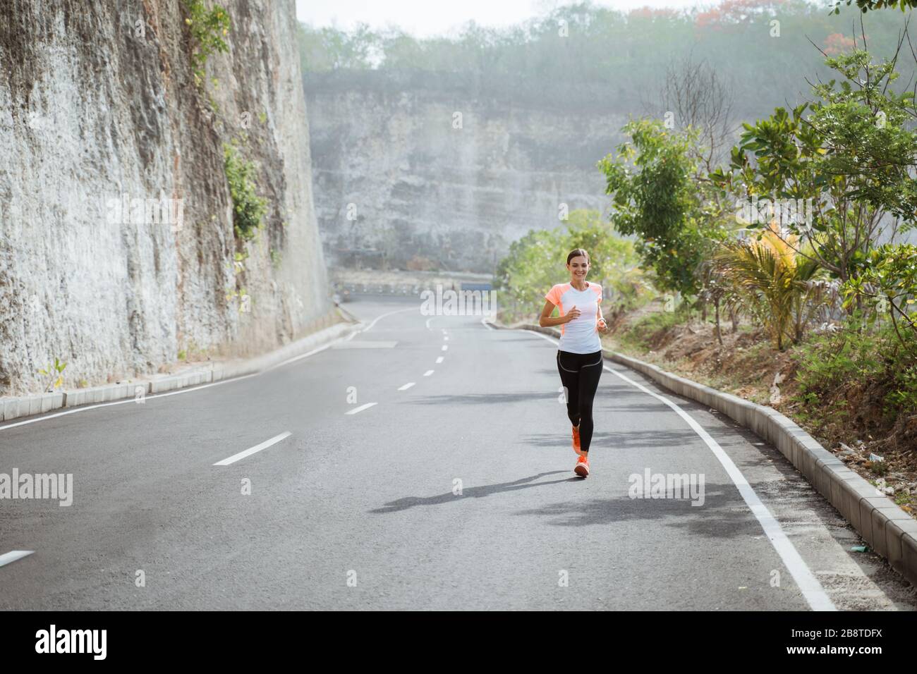 sport woman running on sideroad. fit woman jogging on empty road Stock ...