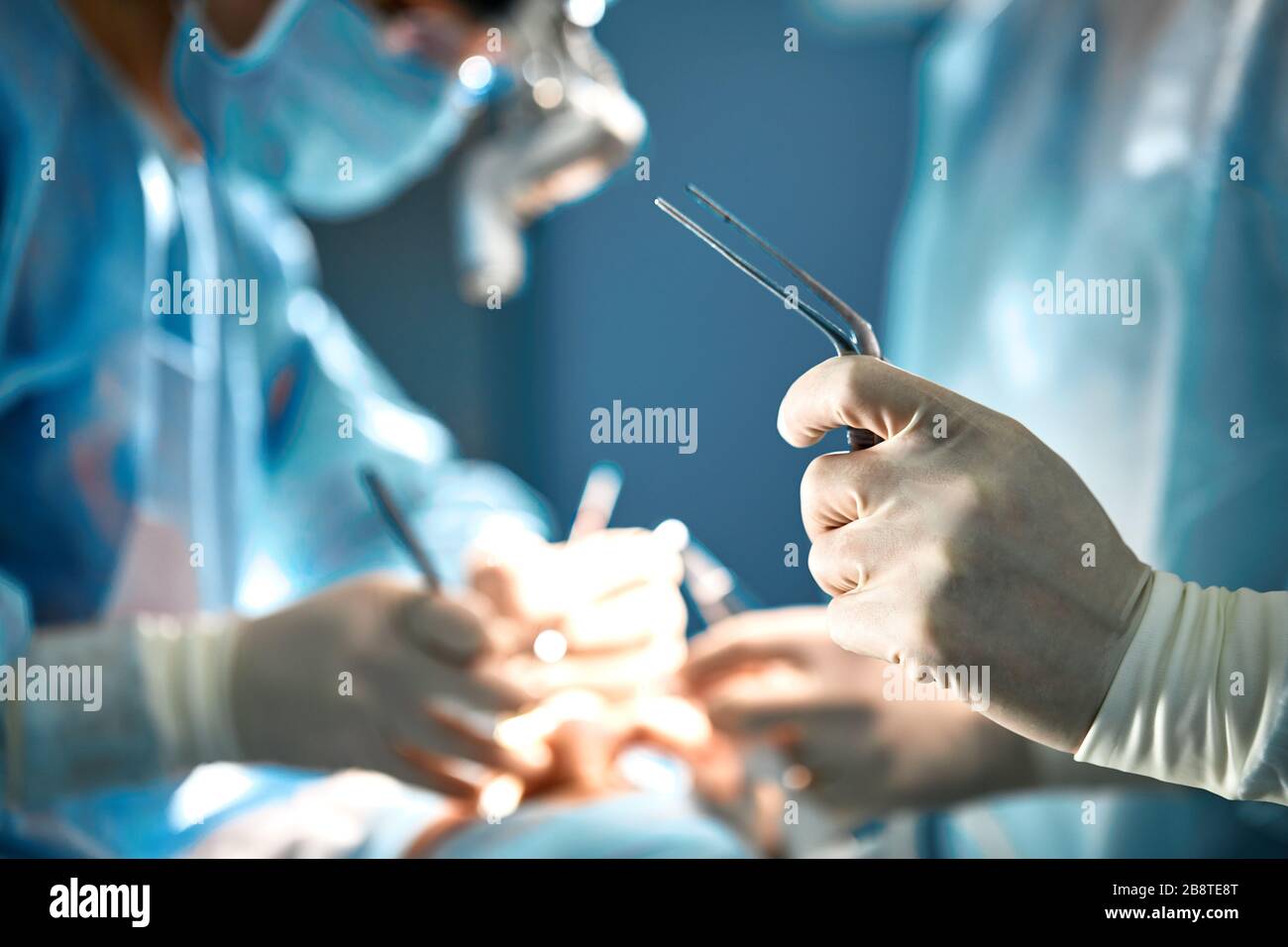 Doctor's hand with latex gloves taking stainless tweezers to help ...