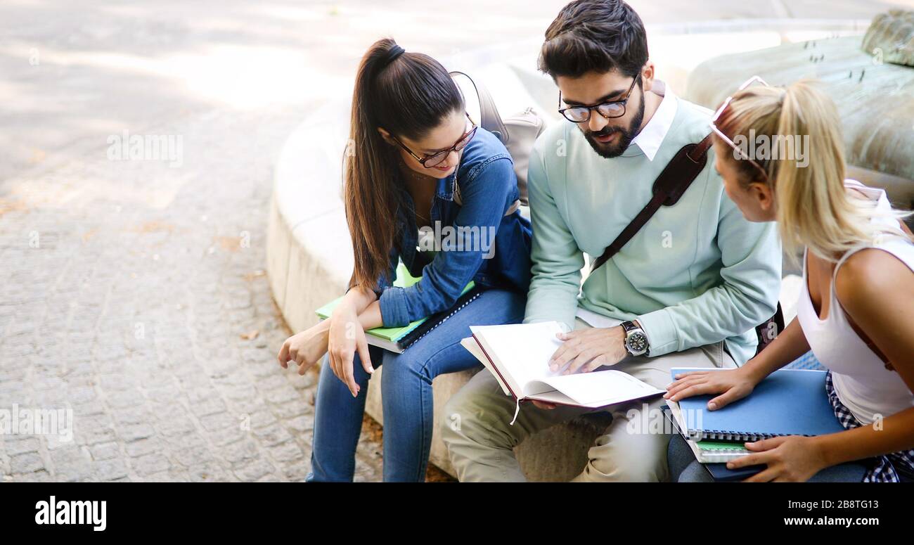 Happy young university students friends studying with books at ...