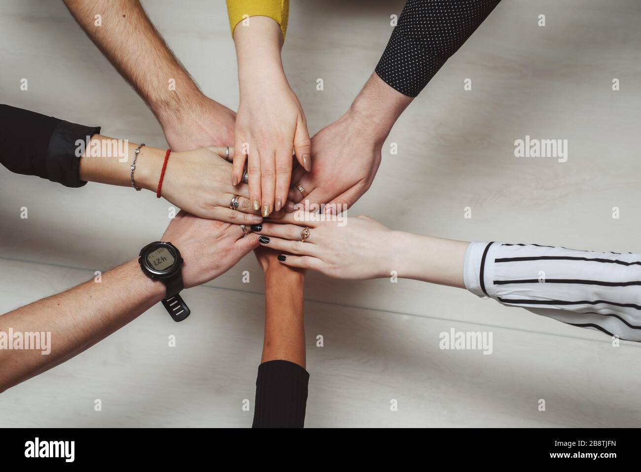 Stack of hands. Unity and teamwork concept. Close up top view of young business people putting ...