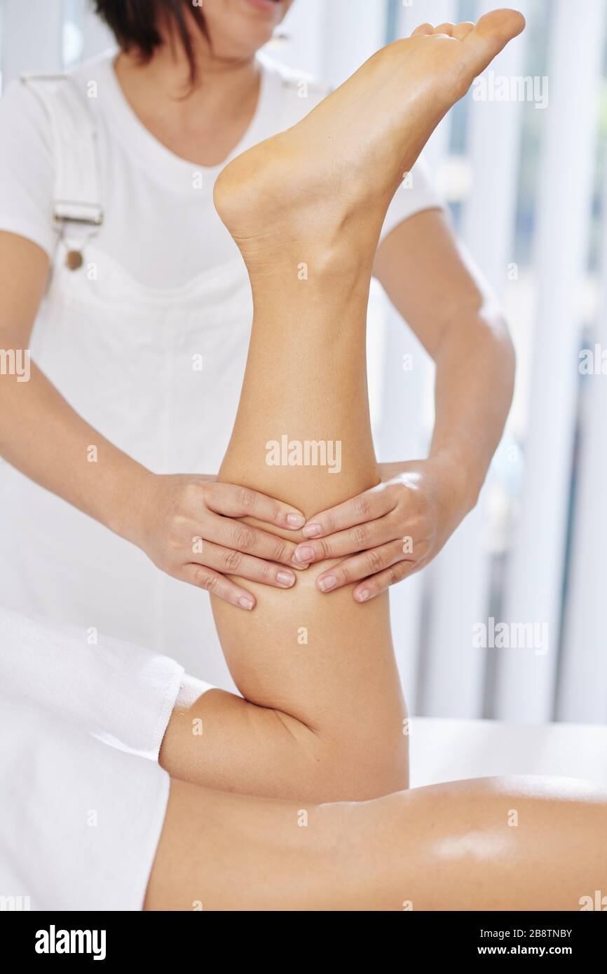 Therapist Massaging Calf Muscles Of Young Woman With Moisturizing