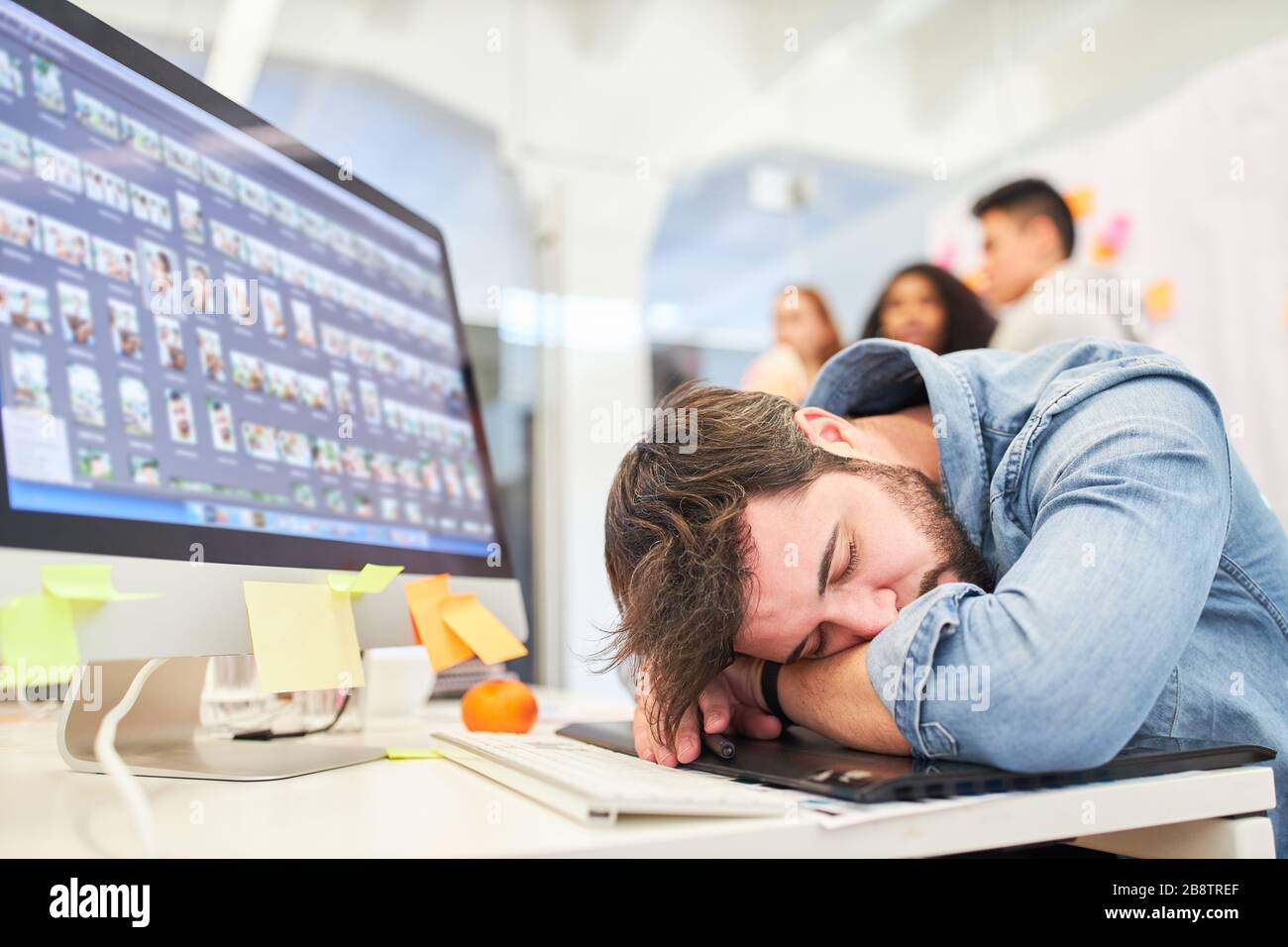 Graphic designer sleeps exhausted in front of PC monitor due to ...