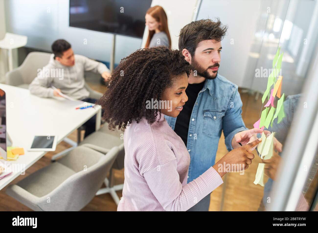 Multicultural web designer team analyzes sticky notes during ...