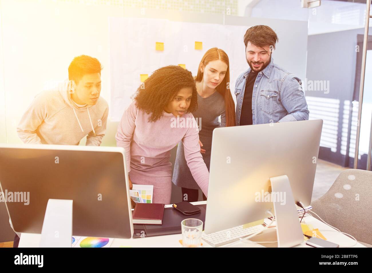 Team of web designers stands together in the office on the computer ...