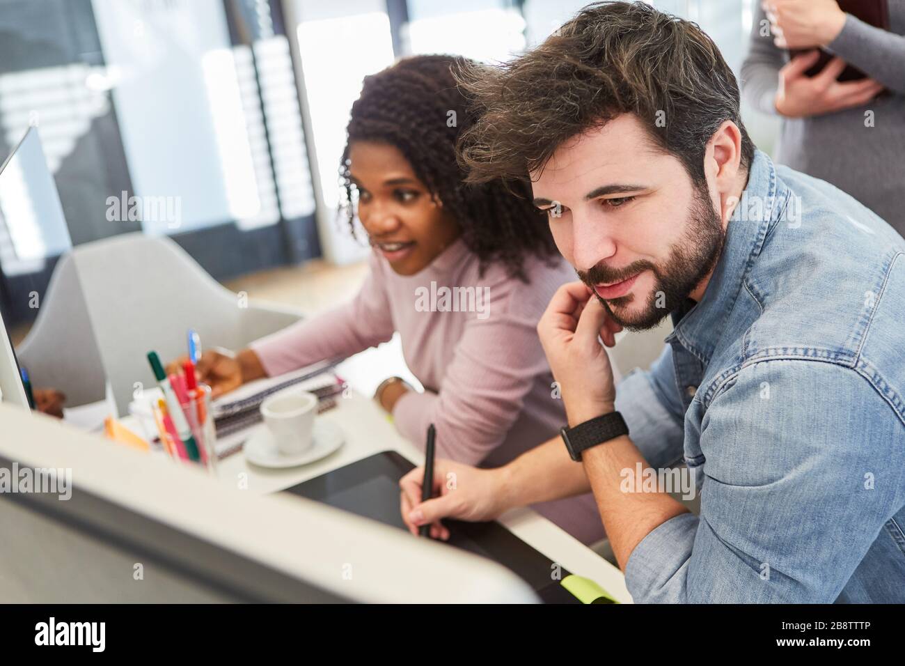 Graphic designer and African colleague on the PC work together on a ...