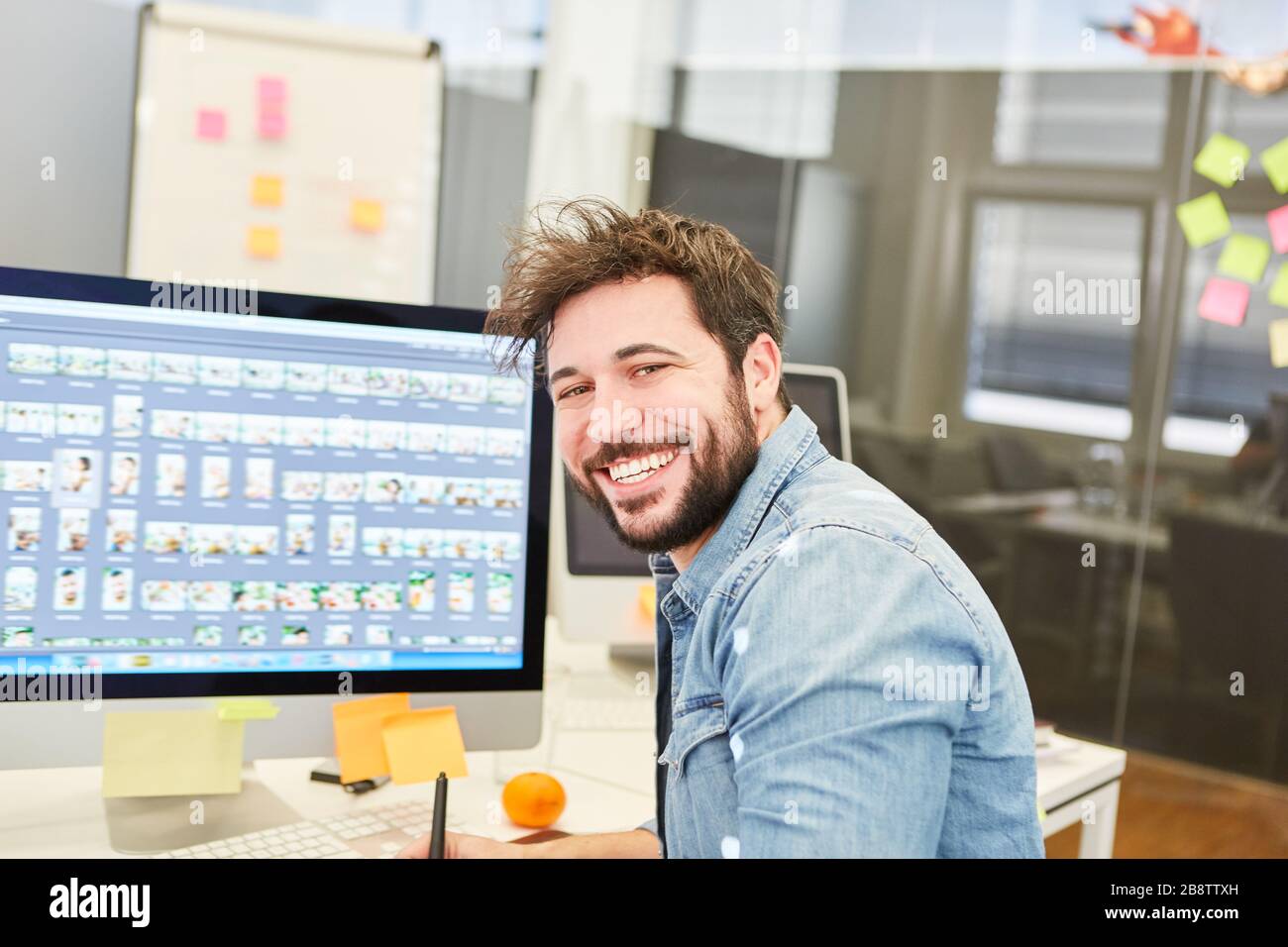 Graphic designer smiling on PC while designing a website in the design ...