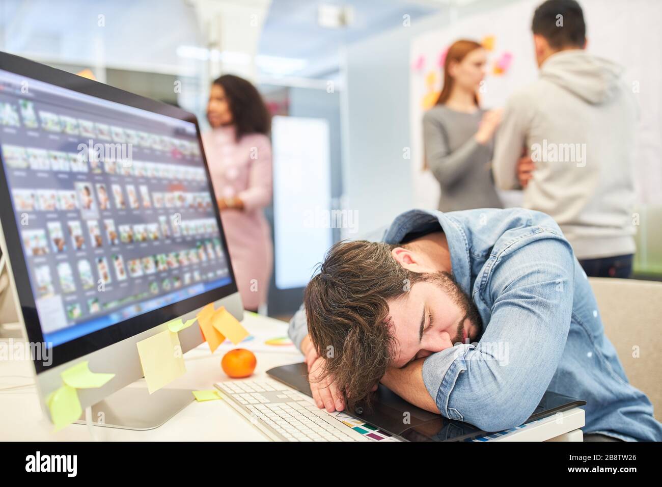 Graphic designer sleeps exhausted in front of the computer monitor due ...