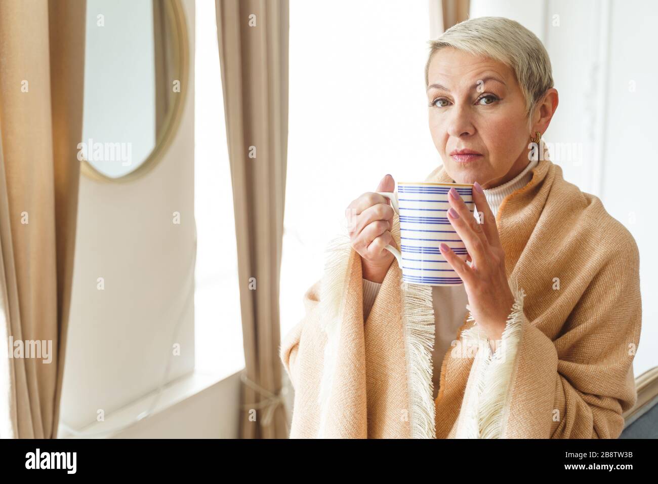 Sad woman holding a mug in her hands Stock Photo - Alamy