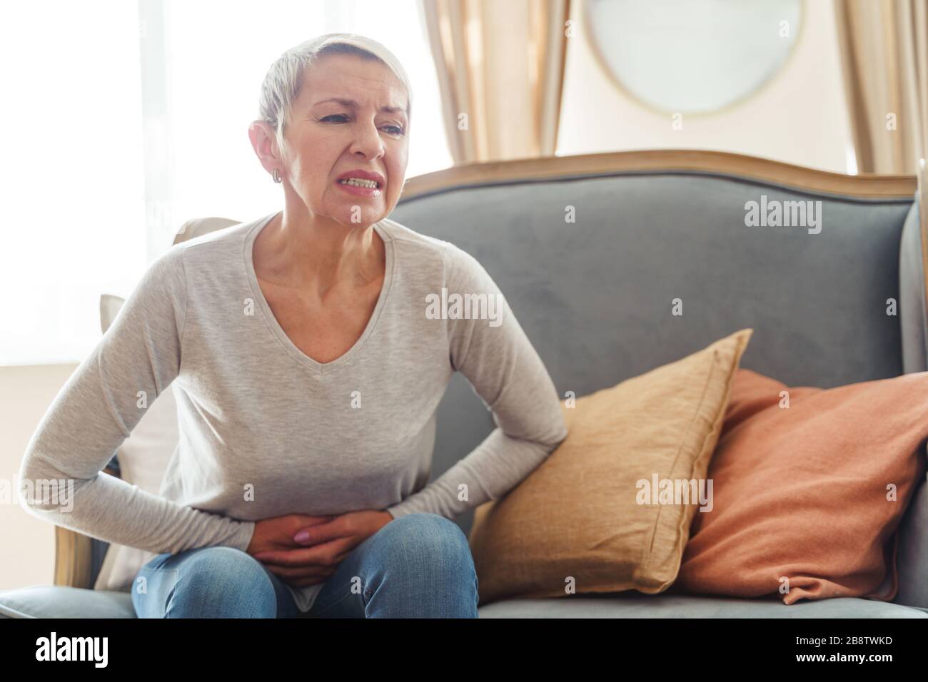 Modern senior woman experiencing severe stomach spasms Stock Photo - Alamy