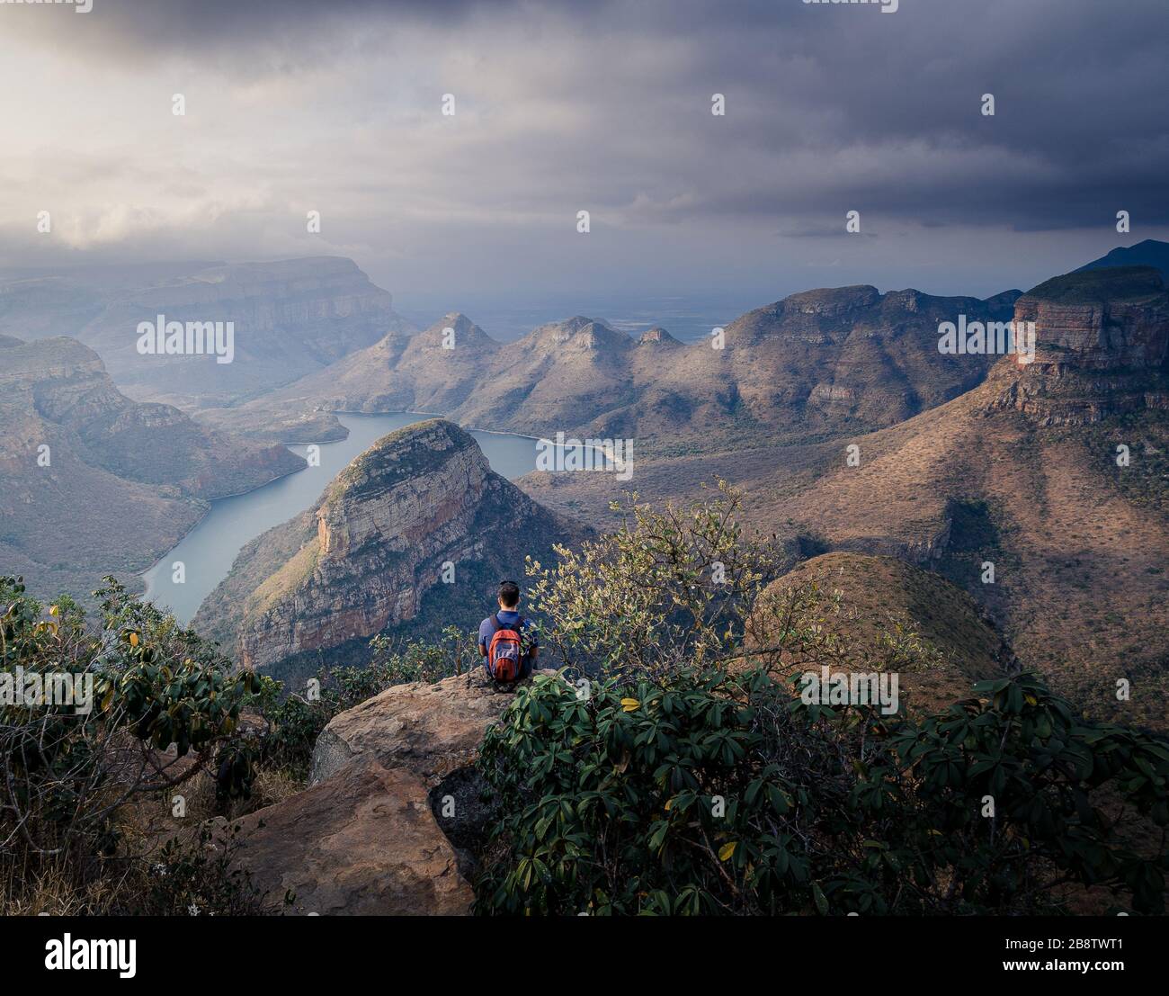 Caucasian man sitting on cliff edge admiring breathtaking view of 3 ...