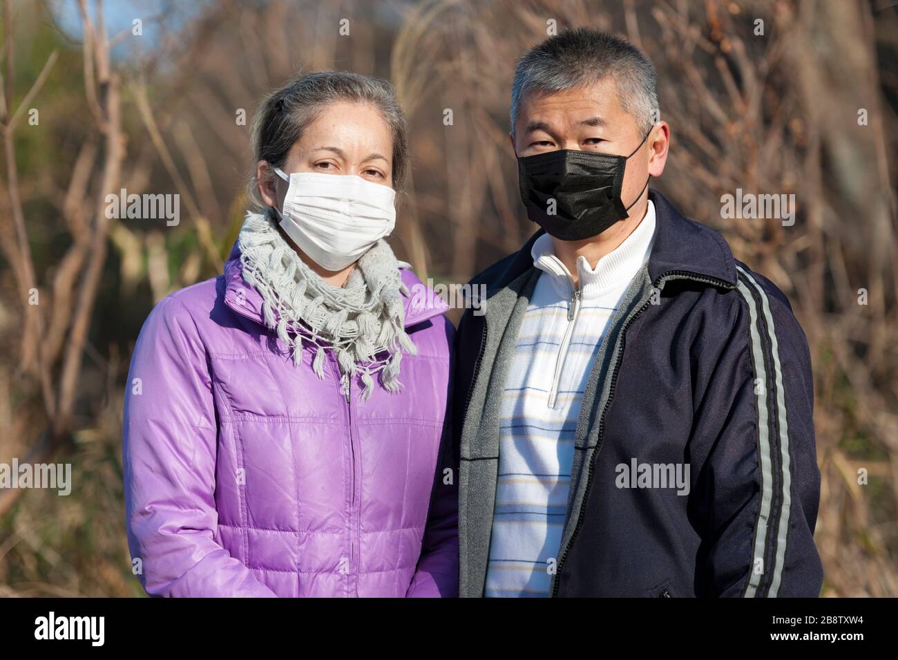 Middle aged couple wearing mask (white mask and black mask) to protect ...
