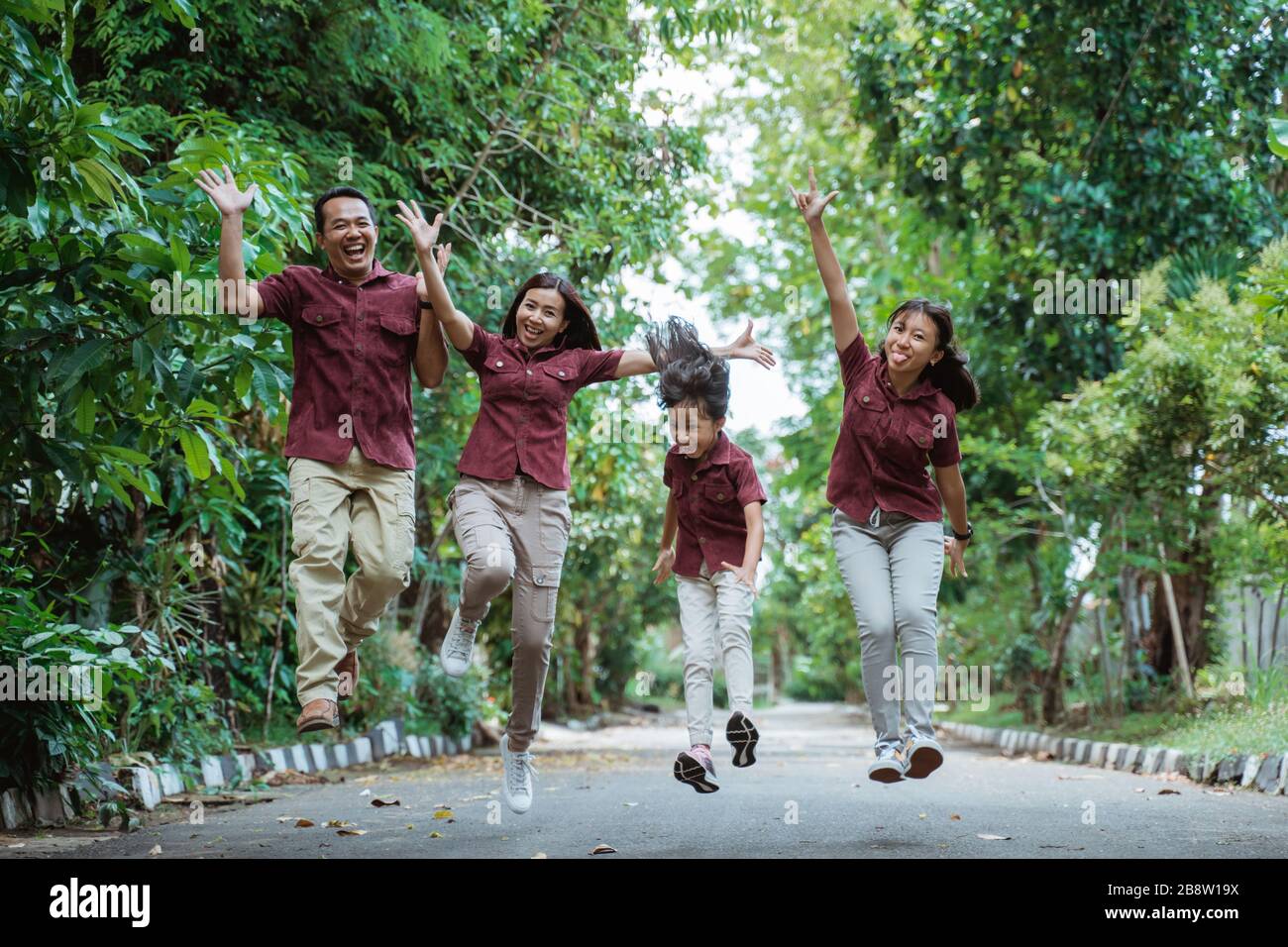 Happy family jumping with raised hands in park during daytime Stock ...