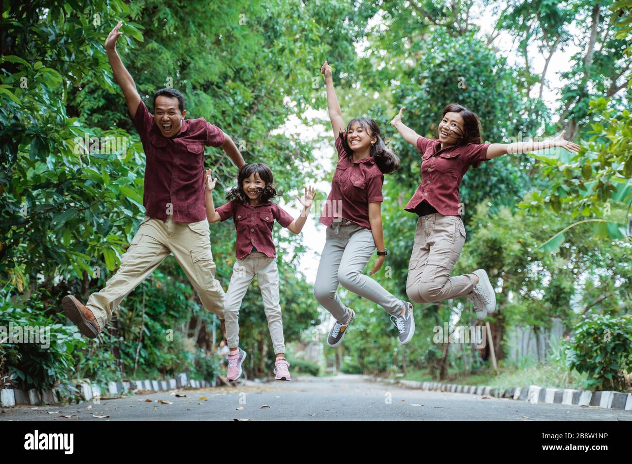 Happy family jumping with raised hands in park during daytime Stock ...