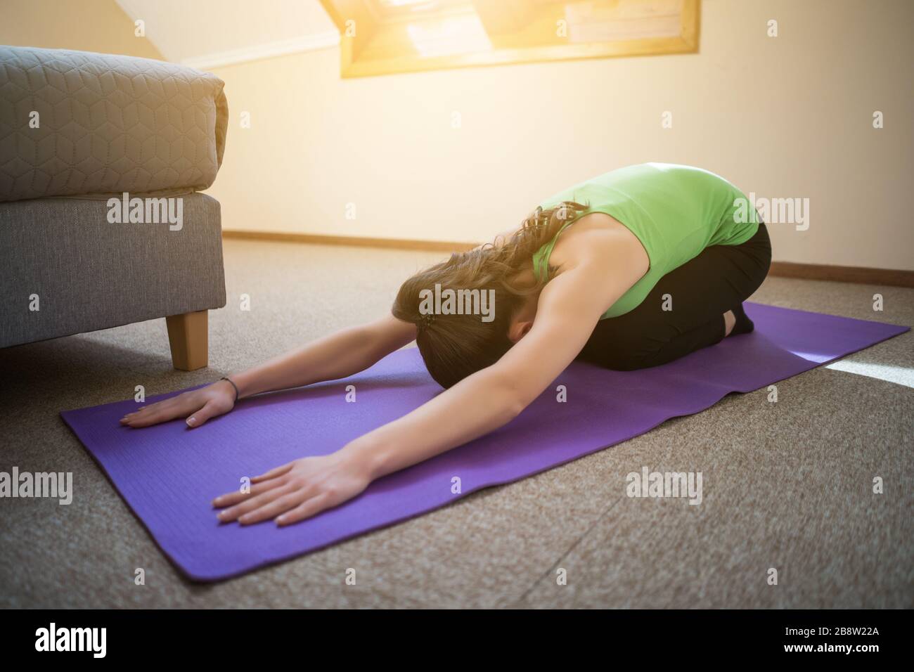 Young woman is practicing yoga at home. Shashankasana / Hare pose Stock ...