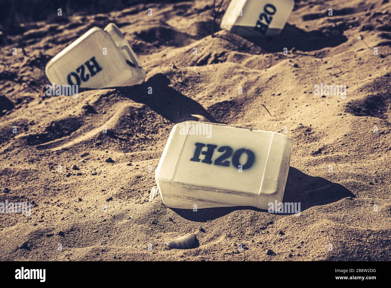 Dirty water cans in the sunburned toxic desert Stock Photo - Alamy