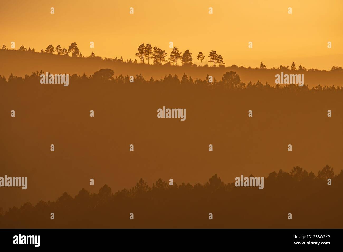 Sunset with orange sky and many layered hills Stock Photo - Alamy