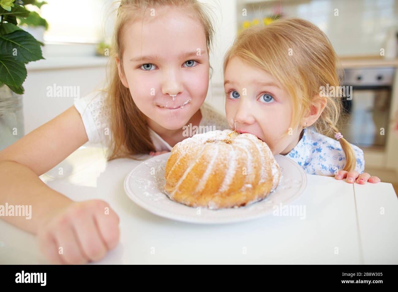 Two children secretly snack on a fresh cake in the kitchen Stock Photo ...