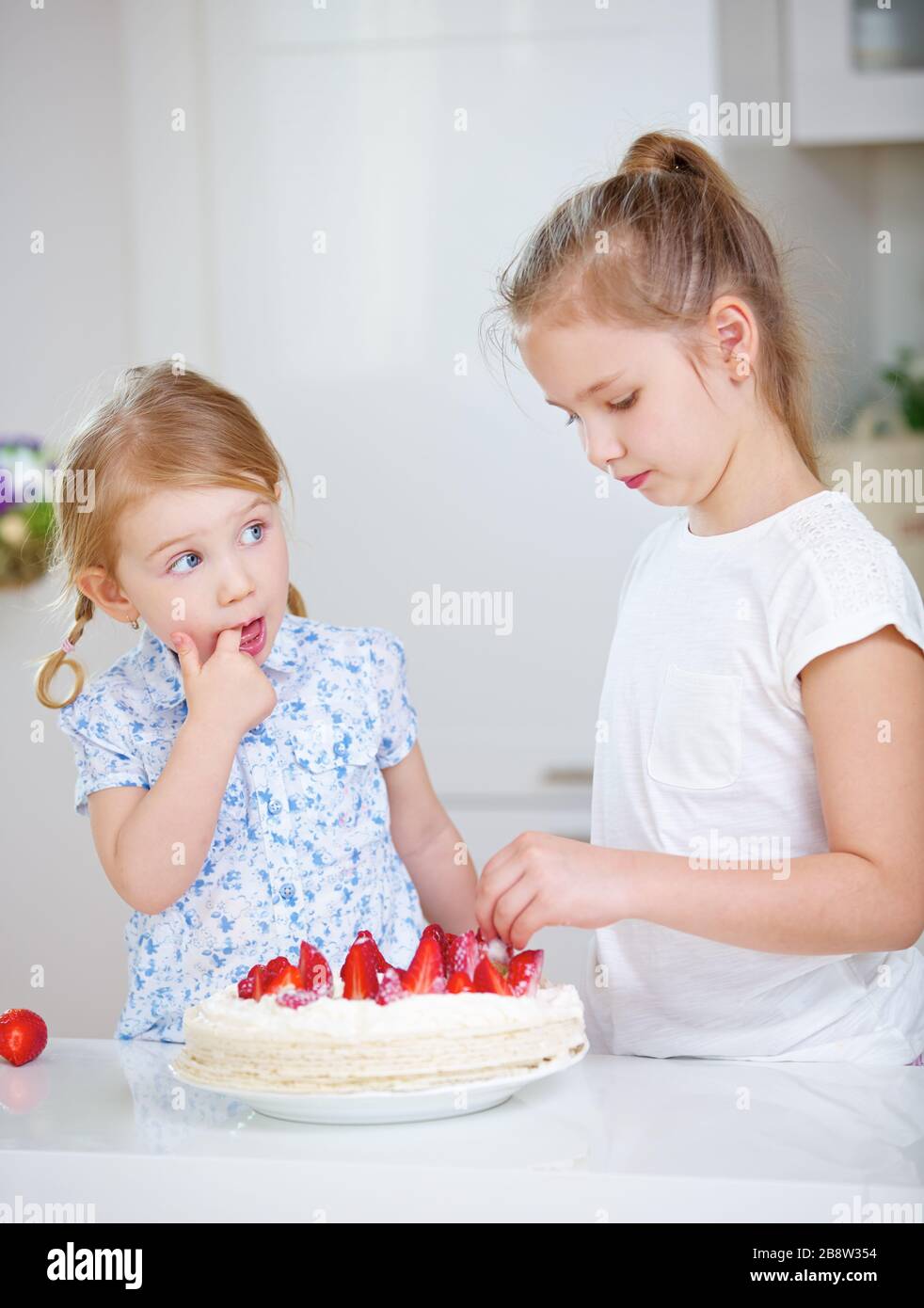 Two children sneak secretly from a strawberry cake in the kitchen Stock ...