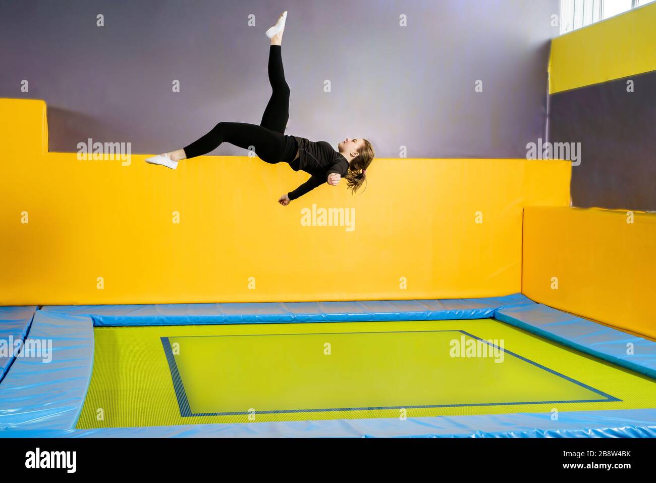 Young woman amateur acrobatic athlete jumping and exercising on a ...