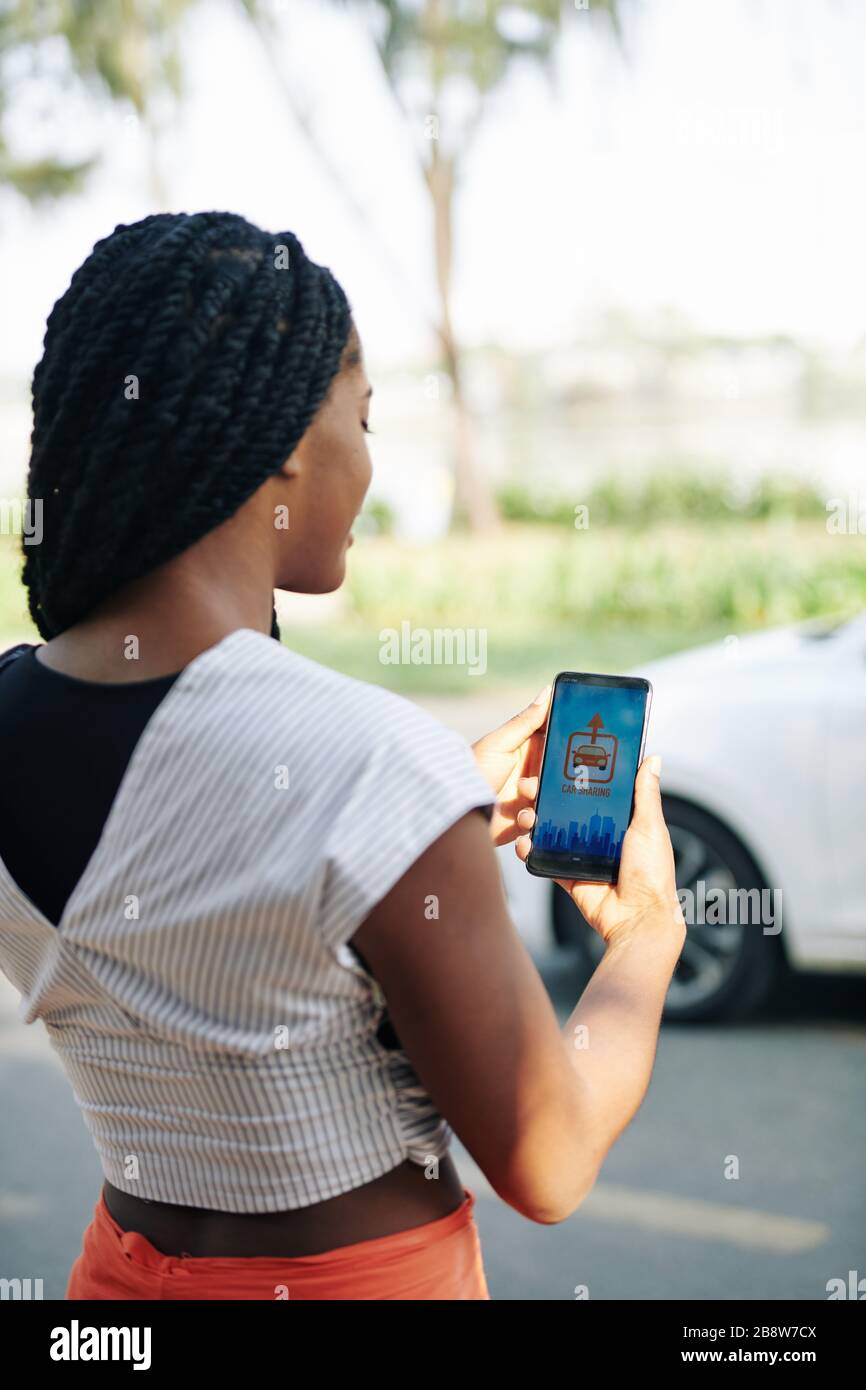 Young woman using car sharing application on smartphone when she needs ...