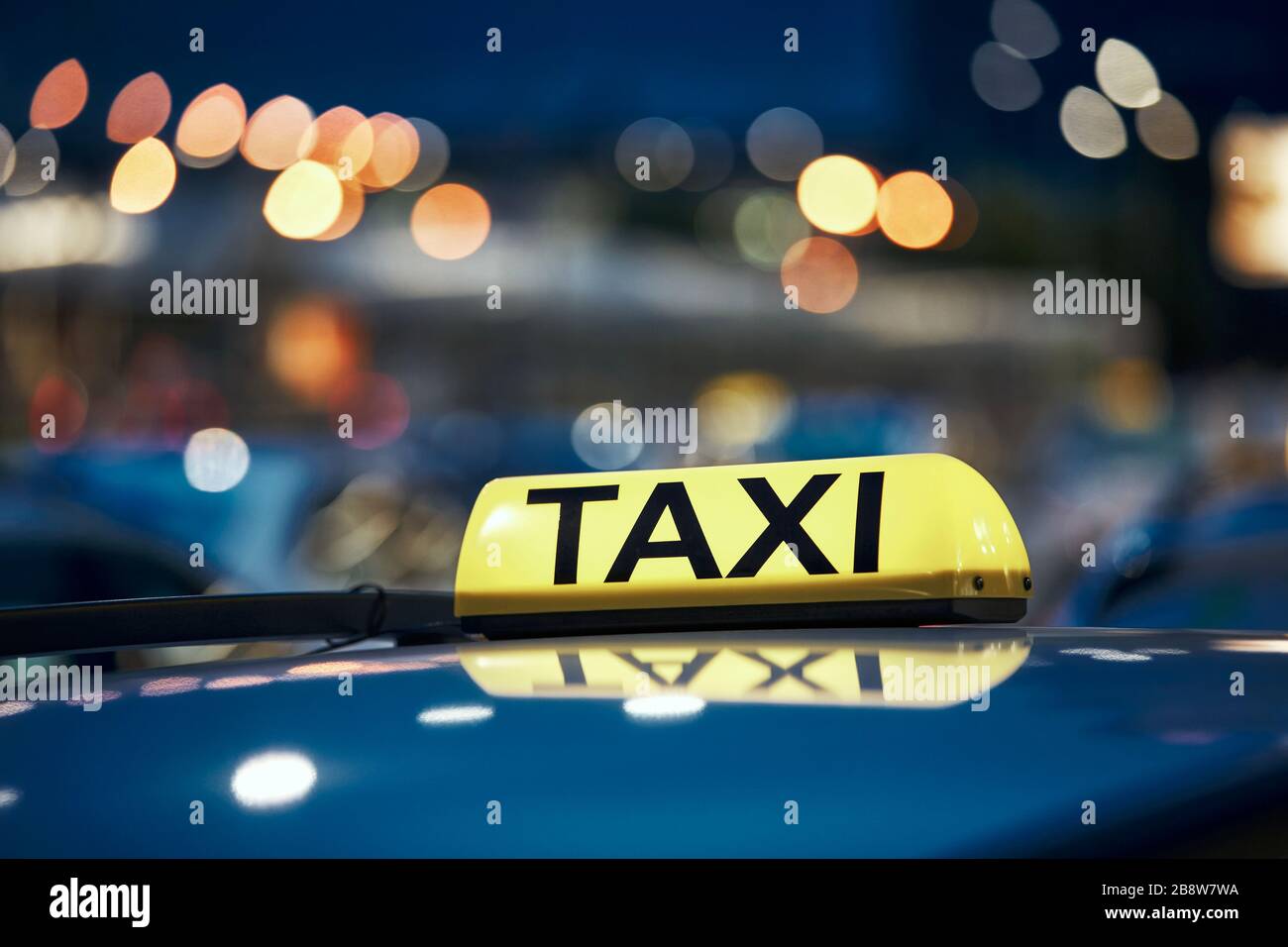 Lighting taxi sign on roof of car on city street at night Stock Photo ...