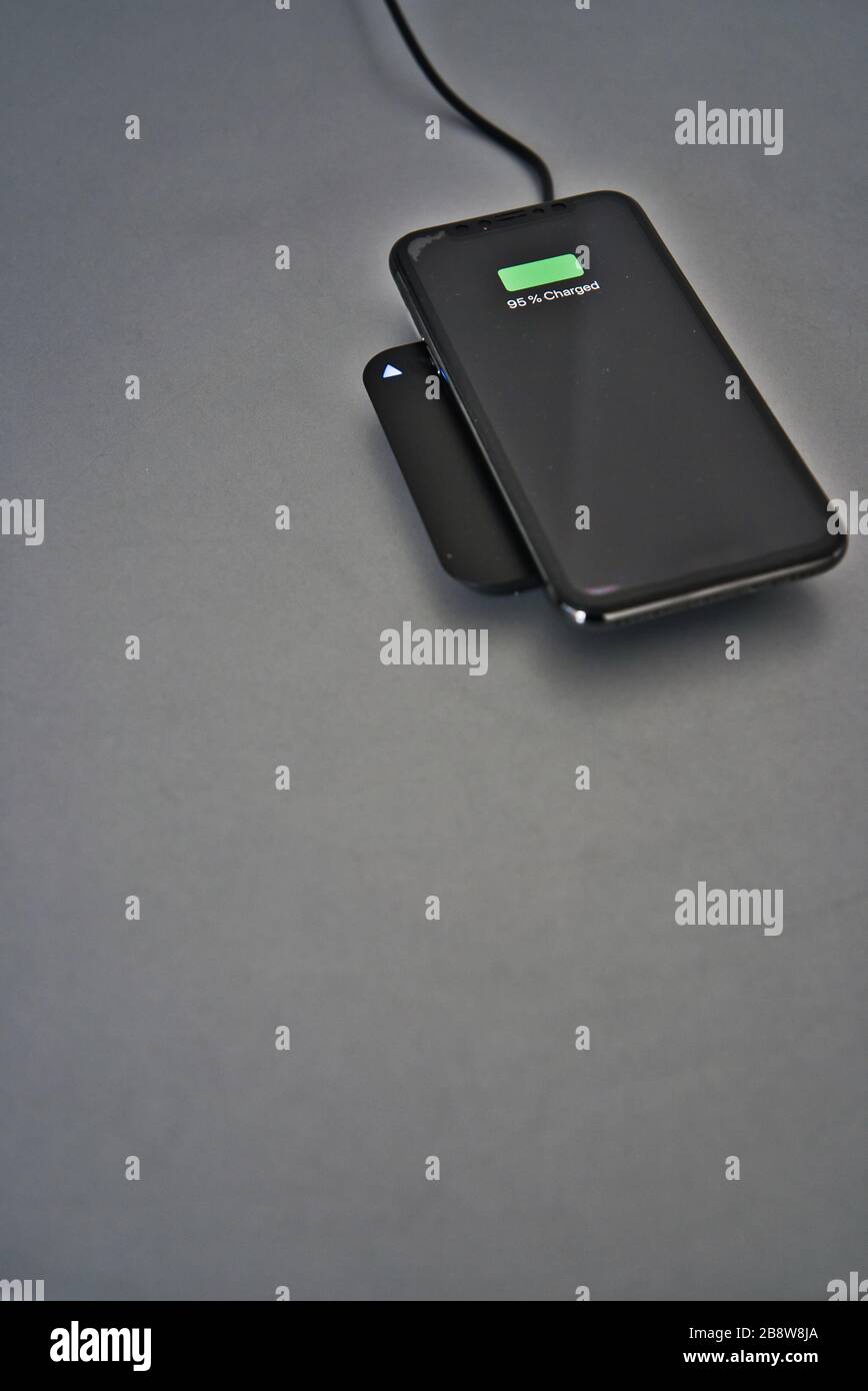 Black desktop wireless charger with charging led charging a smartphone ...