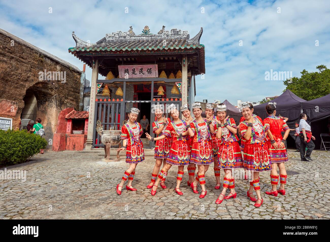 Girls in red traditional costumes posing in front of the Na Tcha Temple ...