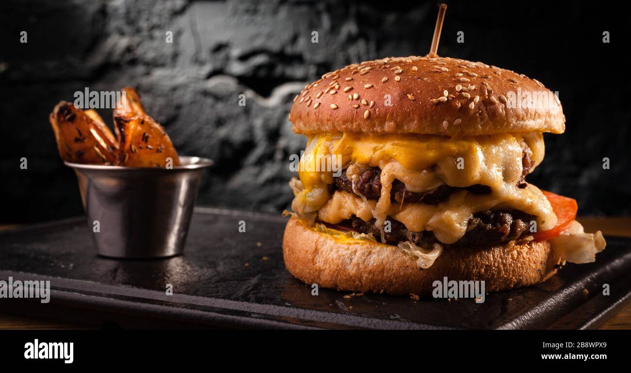 Big cheeseburger with lots of cheese. Stock photo side view of a ...