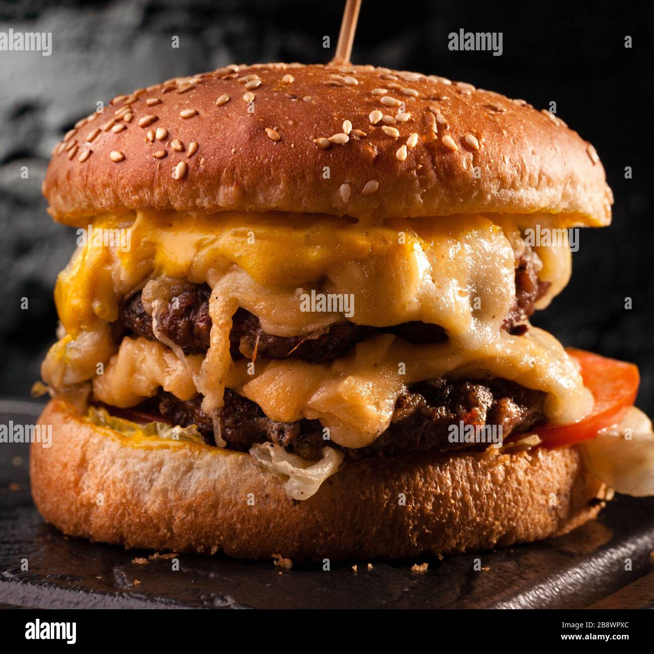 Big cheeseburger with lots of cheese. Stock photo side view of a ...