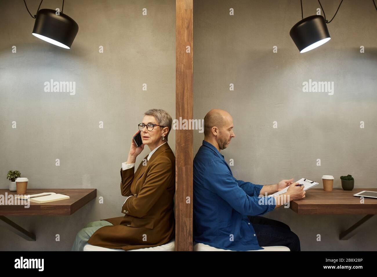 Minimal side view portrait of two adult people separated by wall while ...