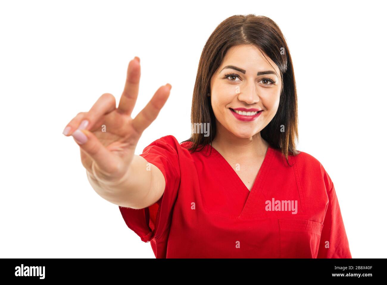 Portrait of beautiful young doctor wearing scrubs showing peace gesture ...
