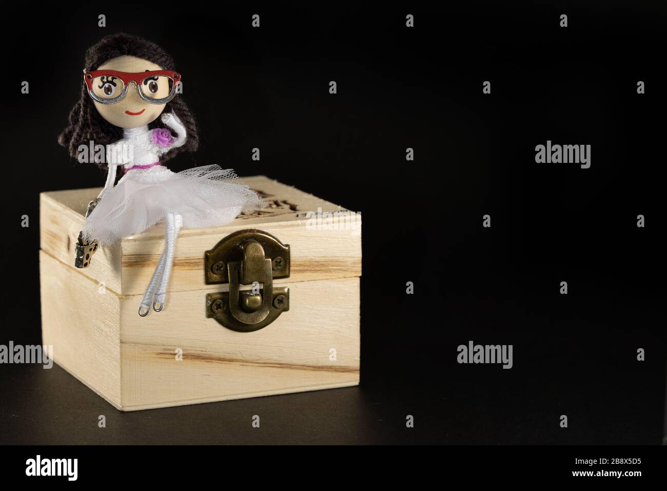 Doll sitting on a wooden treasure chest. Girl protect the treasure ...