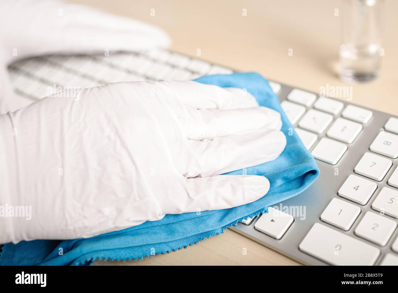 Hand with gloves cleaning a keyboard with disinfectant. COVID-19 ...