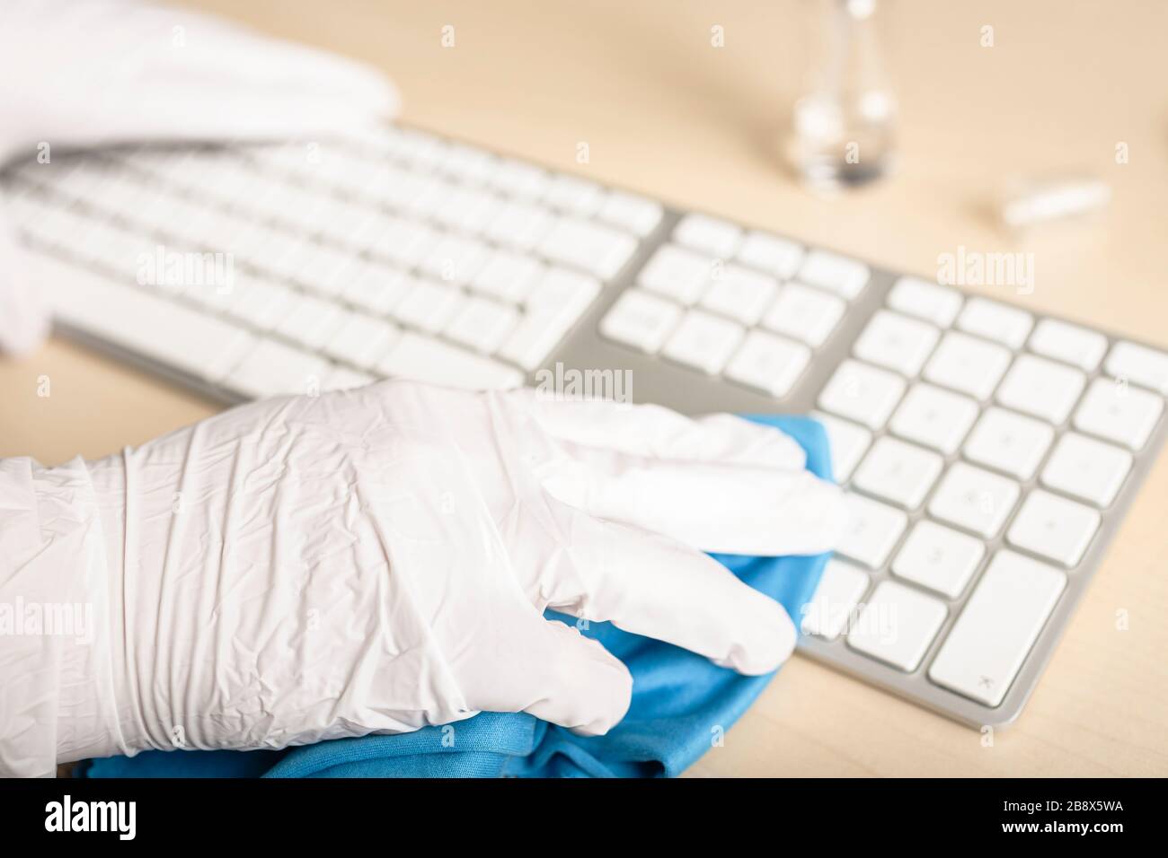 Hand with gloves cleaning a keyboard with disinfectant. COVID-19 ...