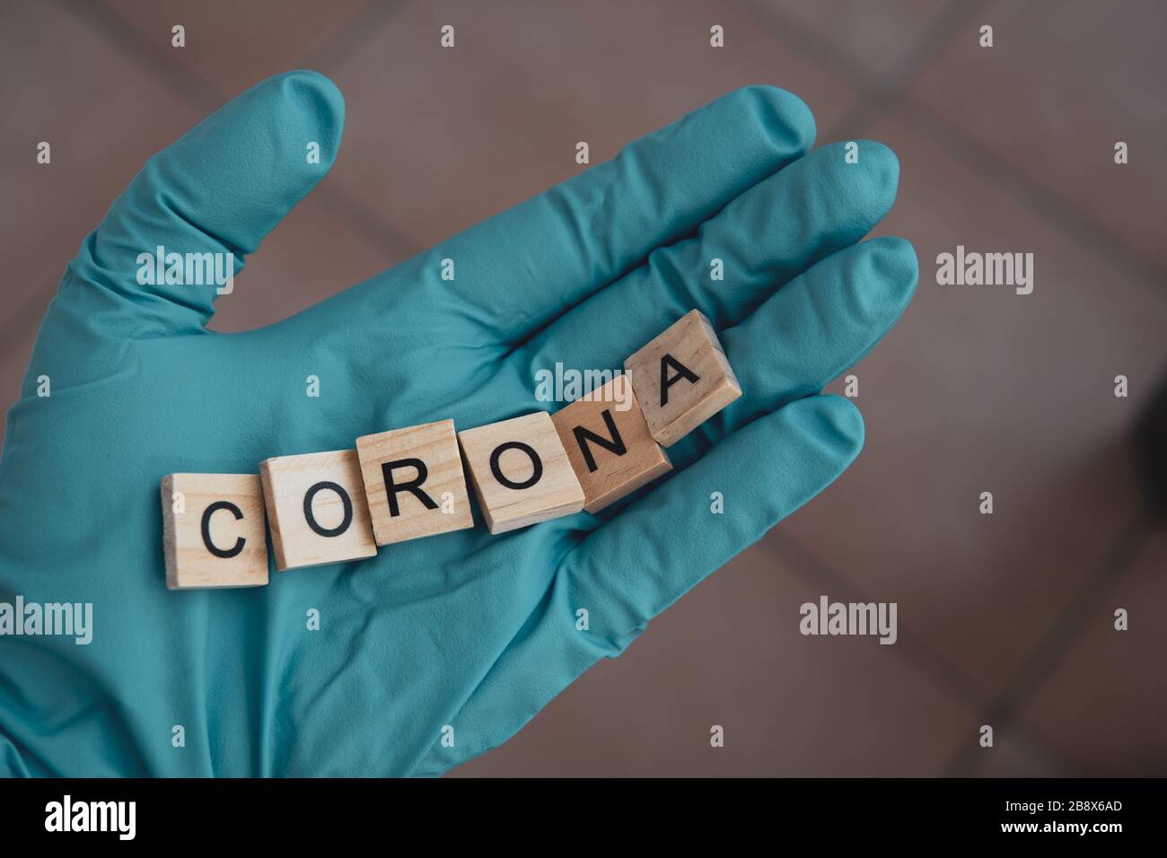 a hand with a glove on holds Scrabble bricks, which form the word ...
