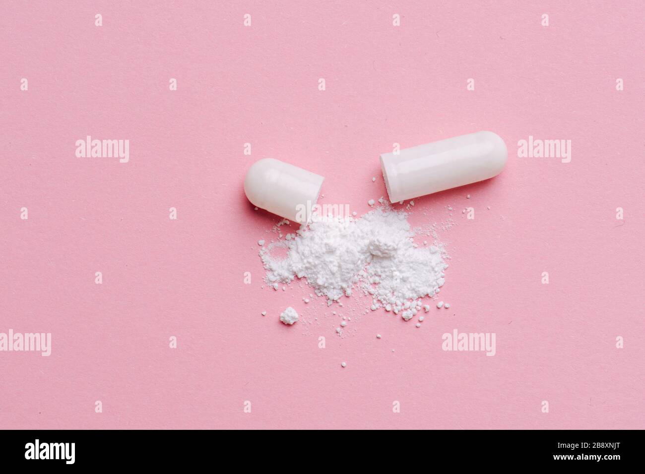 Drug capsule broken in half with powder ingredient sprinkled over ...