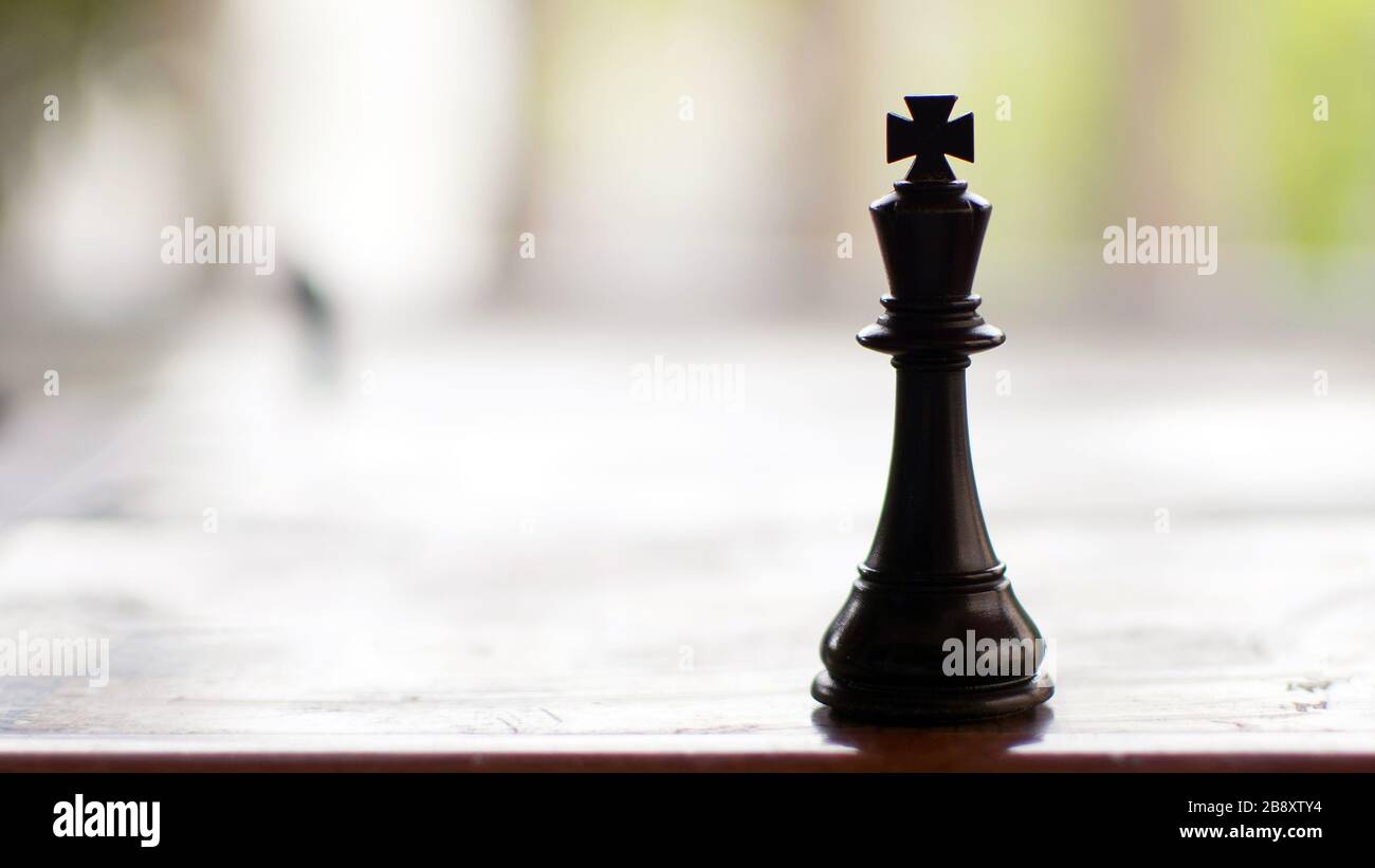 This is a shot of a king chess piece shot alone on a chess board with a ...