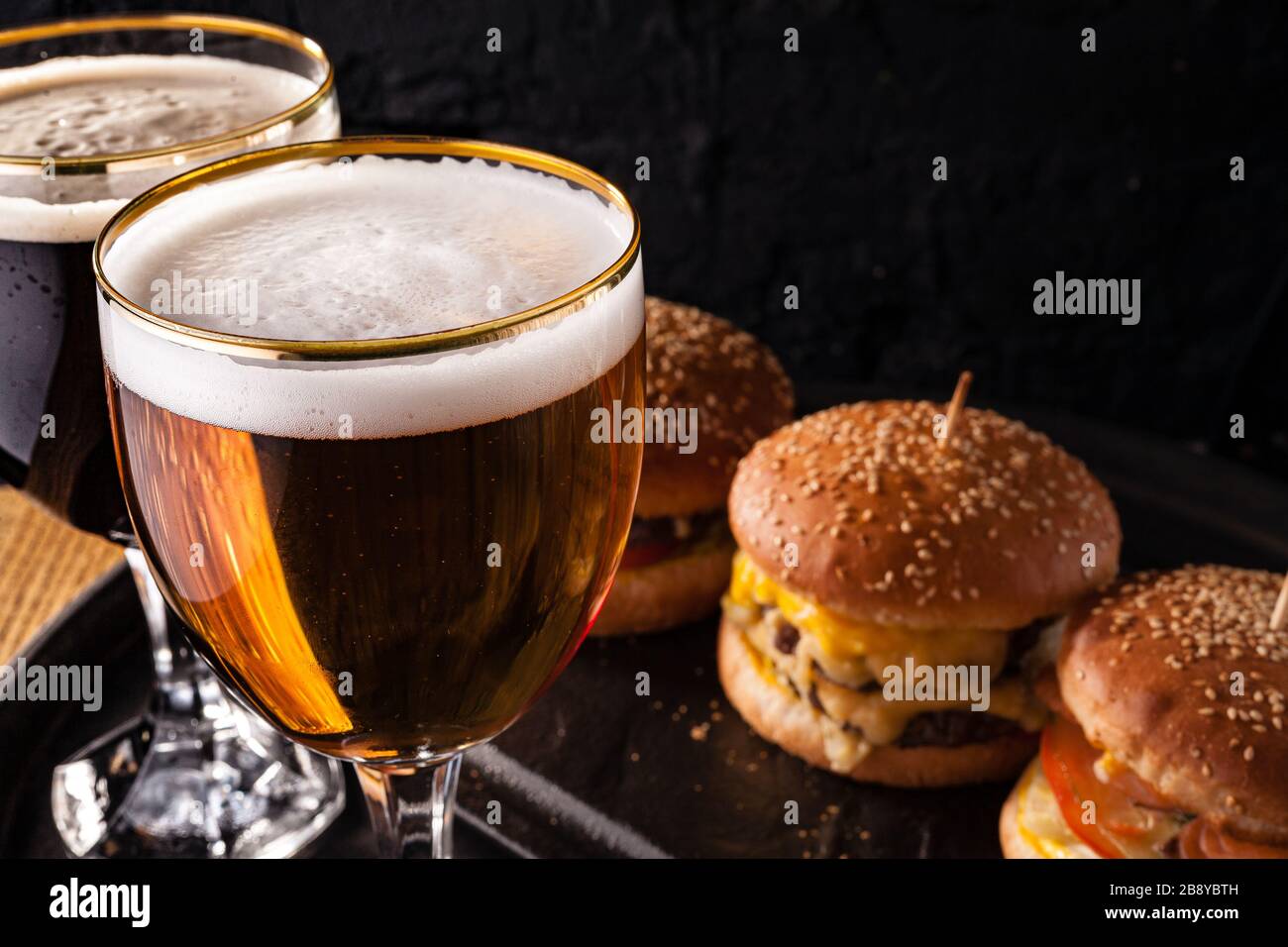 Cold beer in a glass and a snack in the form of juicy large burgers ...