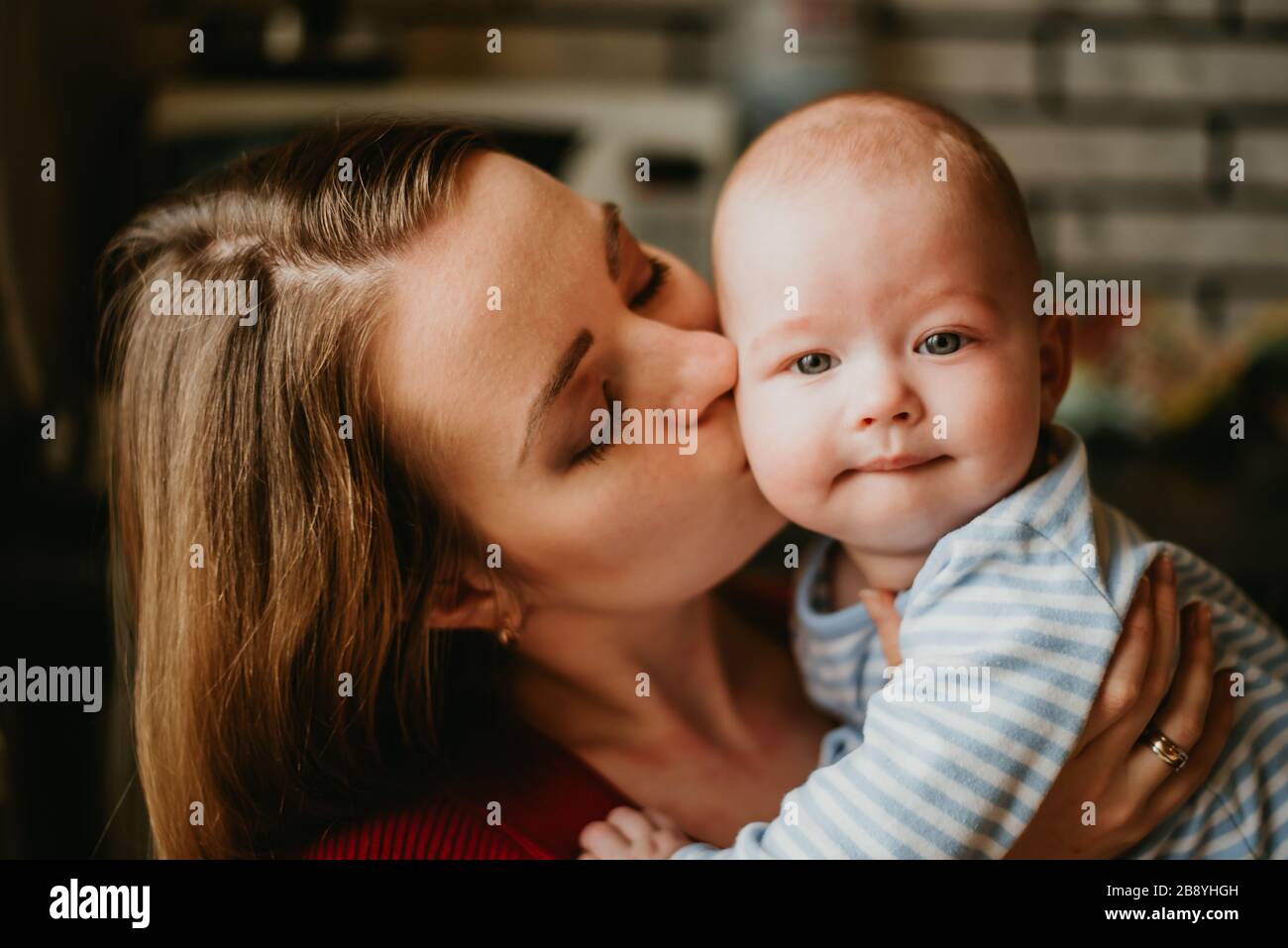 A mom holds a child in her arms. A mother kisses a toddler. A young ...