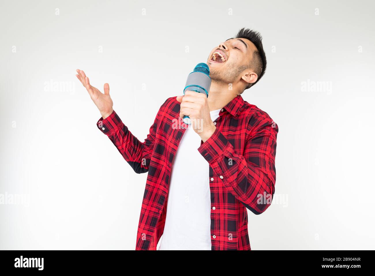 joyful singer man in a shirt smiles and sings into a microphone on a white background Stock ...