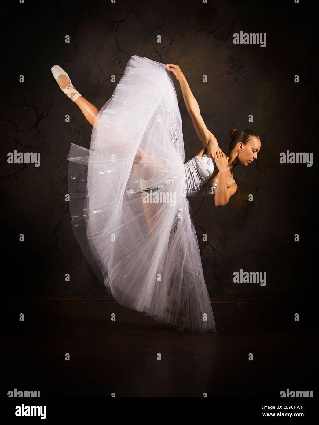 Slender woman in a white corset tutu dancing ballet. Studio shooting on ...