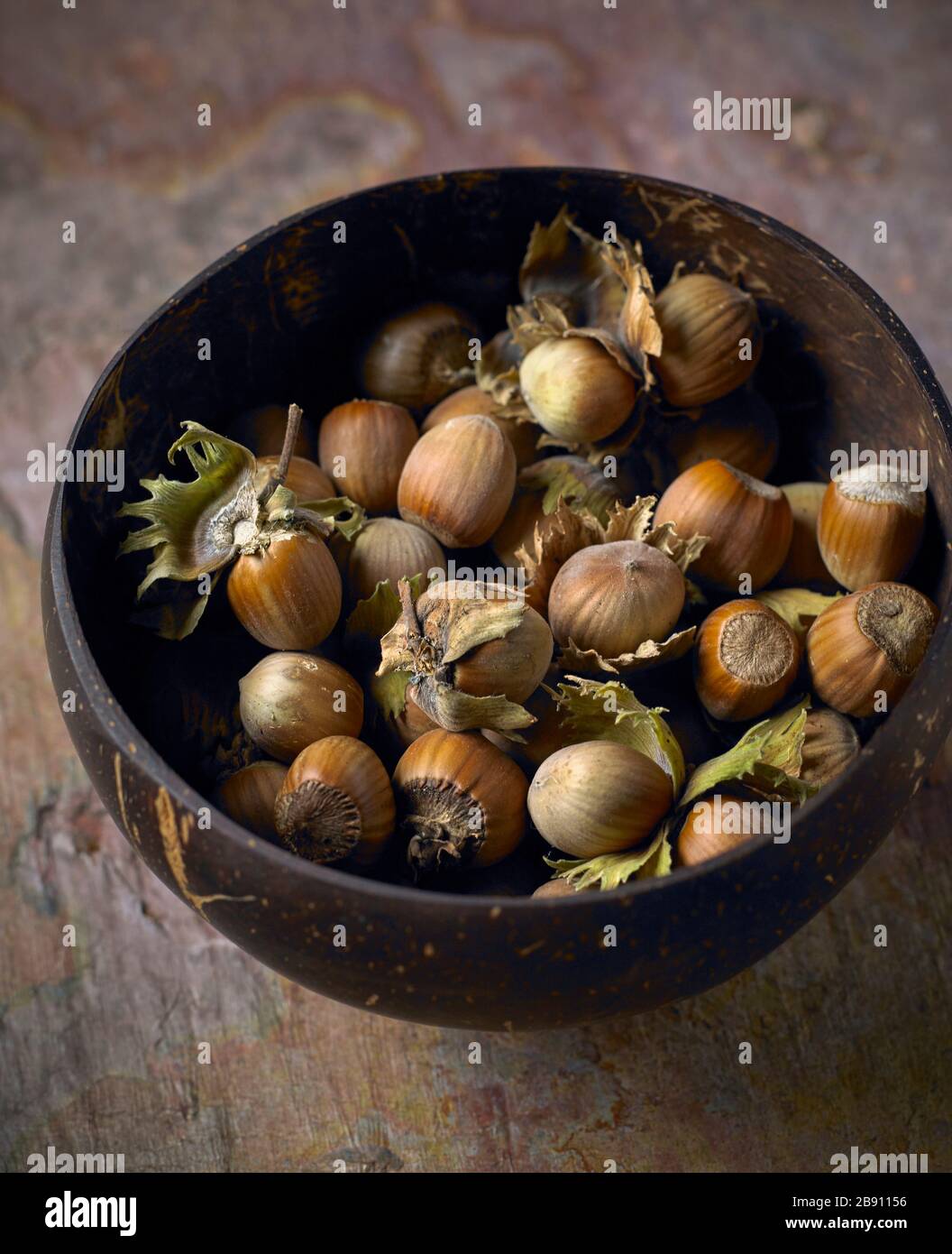 Foraged Cobb nuts in a coconut shell bowl Stock Photo - Alamy