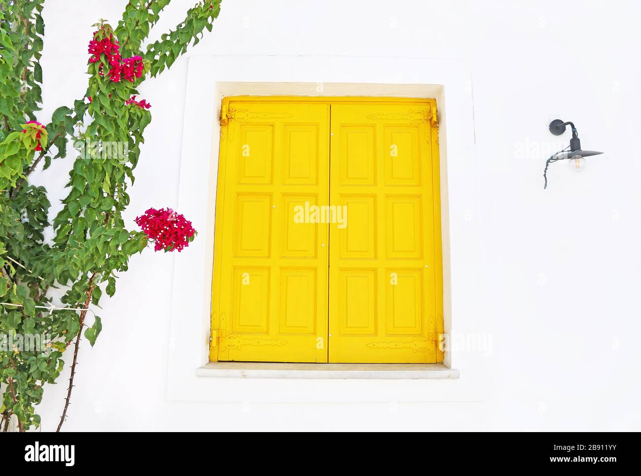 traditional old yellow window with bougainvillea flowers at Koufonisia ...